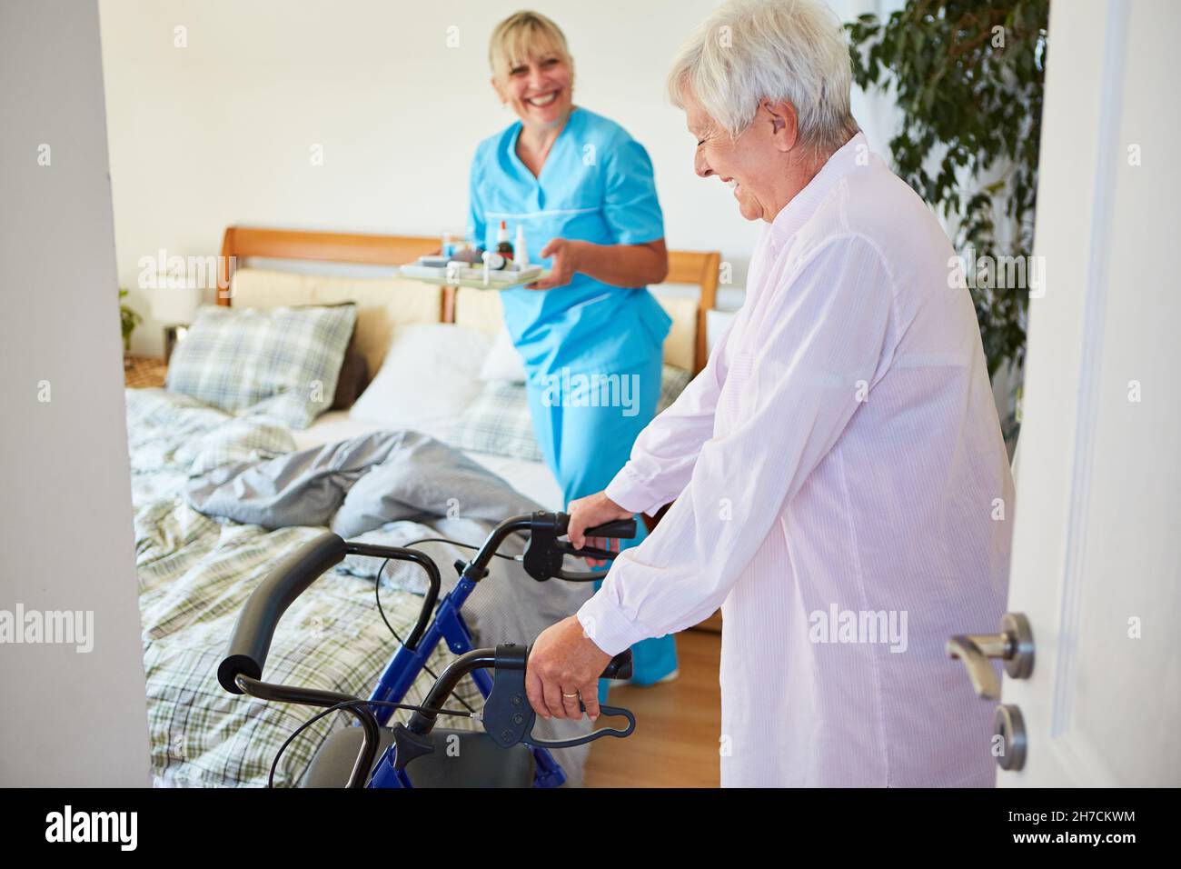 Senior woman patient with rollator in the rehab clinic and nurse with ...