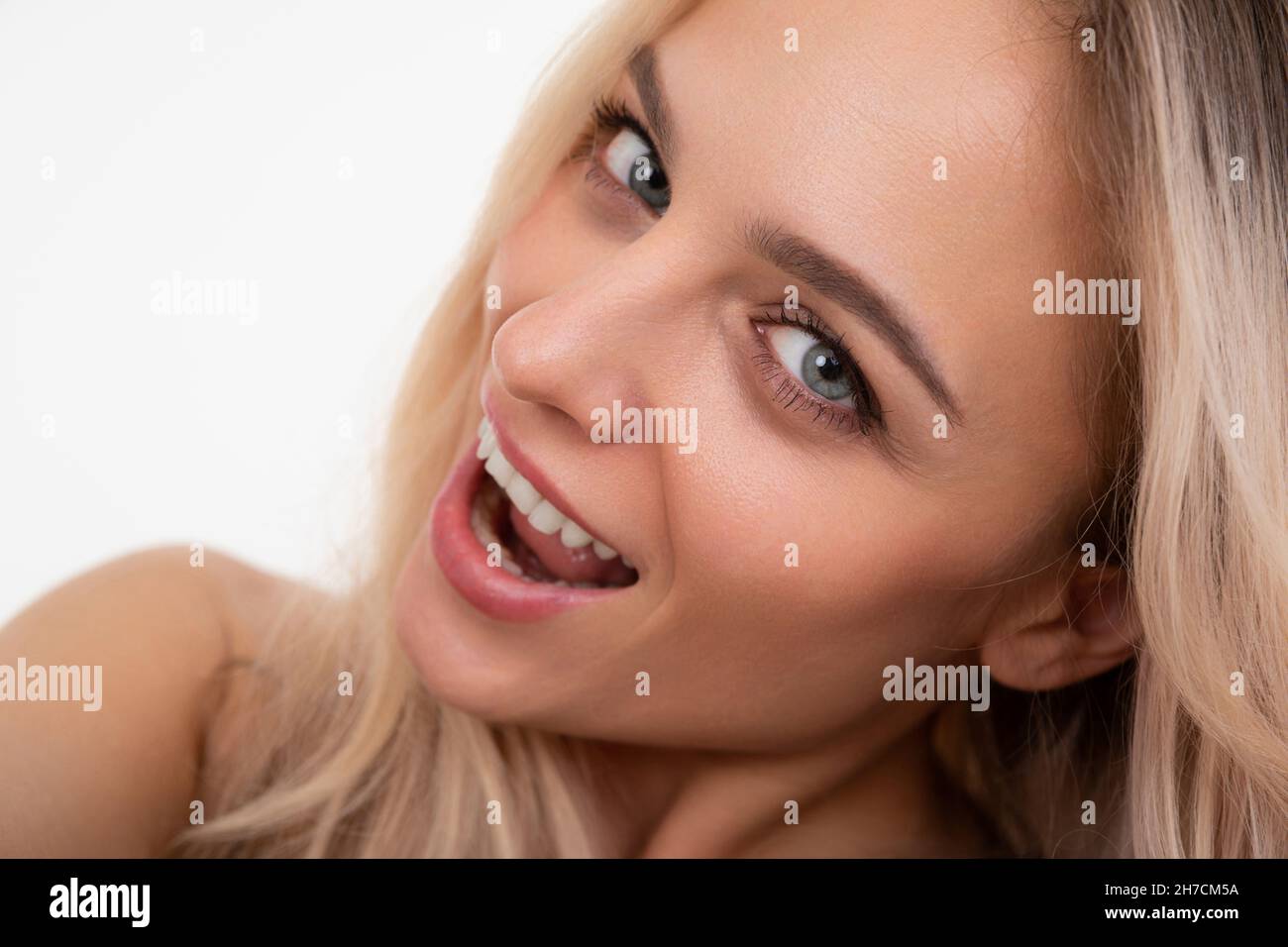 half-turn portrait of young woman smiling with teeth look at the camera ...