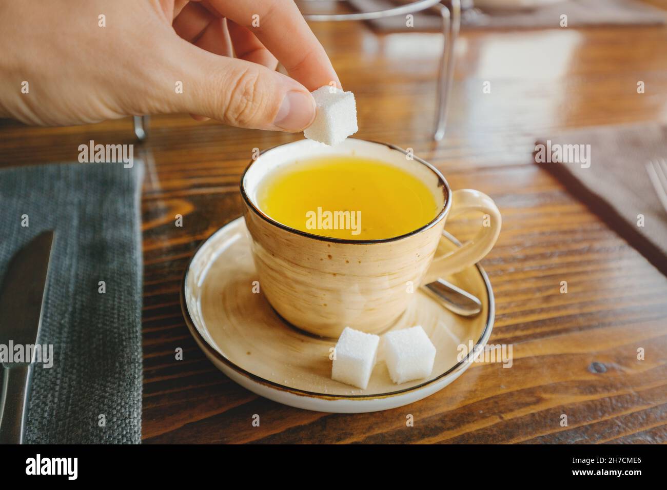 A man puts white refined sugar in green herbal tea. The concept of ...