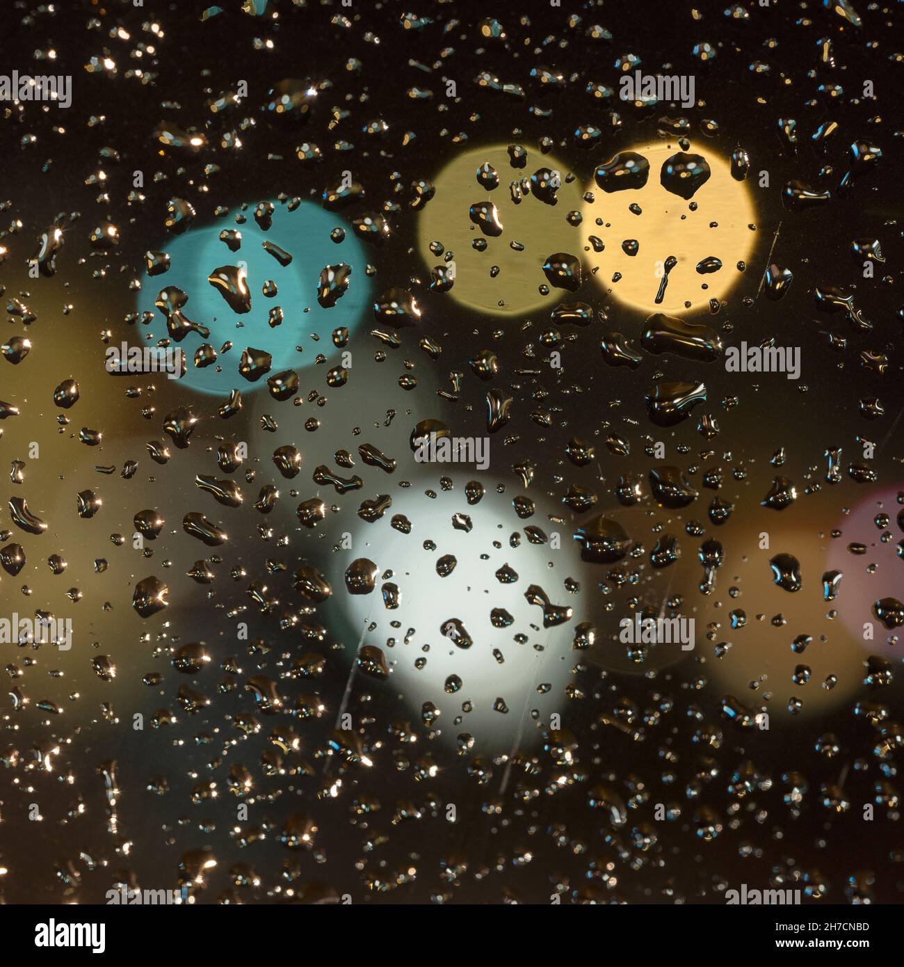 colorful diffuse unsharp lights behind glass window with rain drops ...