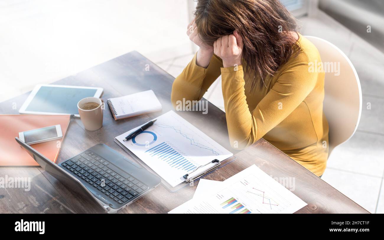 Stressed businesswoman sitting in office with hands on forehead, light ...
