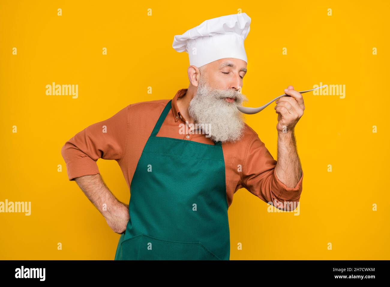 Portrait of attractive dreamy grey-haired man chef tasting lunch fast ...