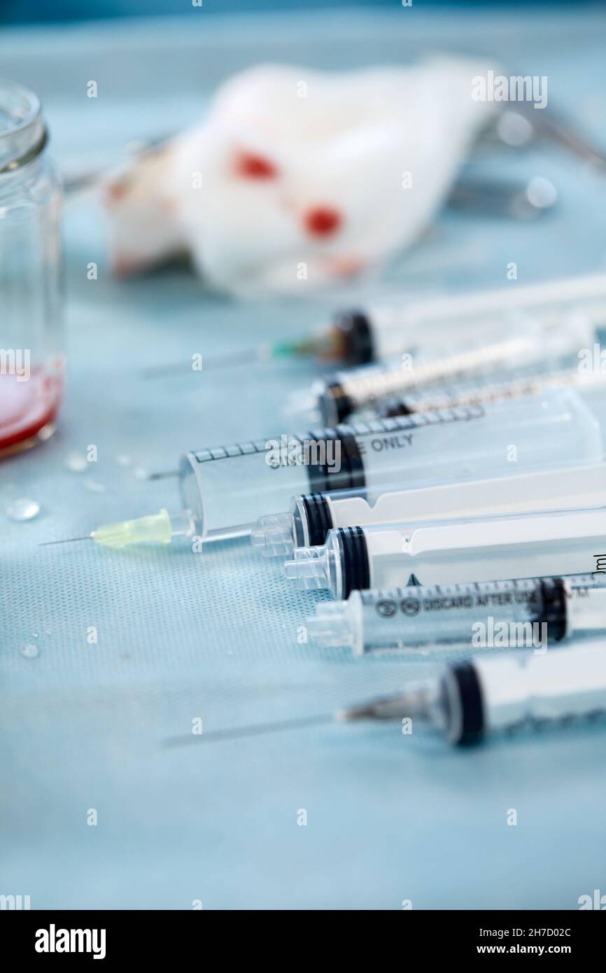 Many syringes on a blue sheet in operation room. Different sizes of ...