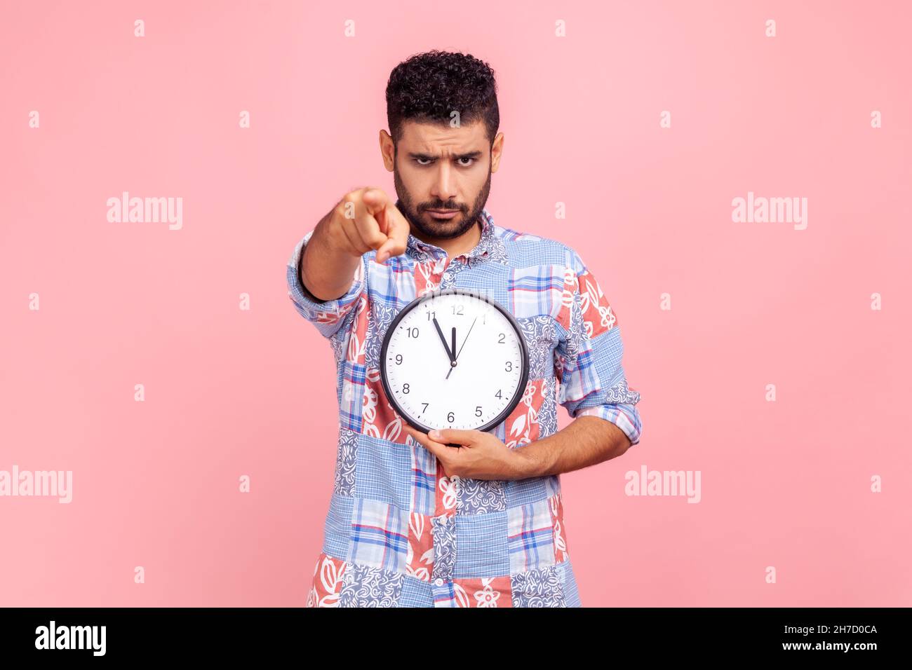 Strict bossy dark haired young adult man with beard holding wall clock ...