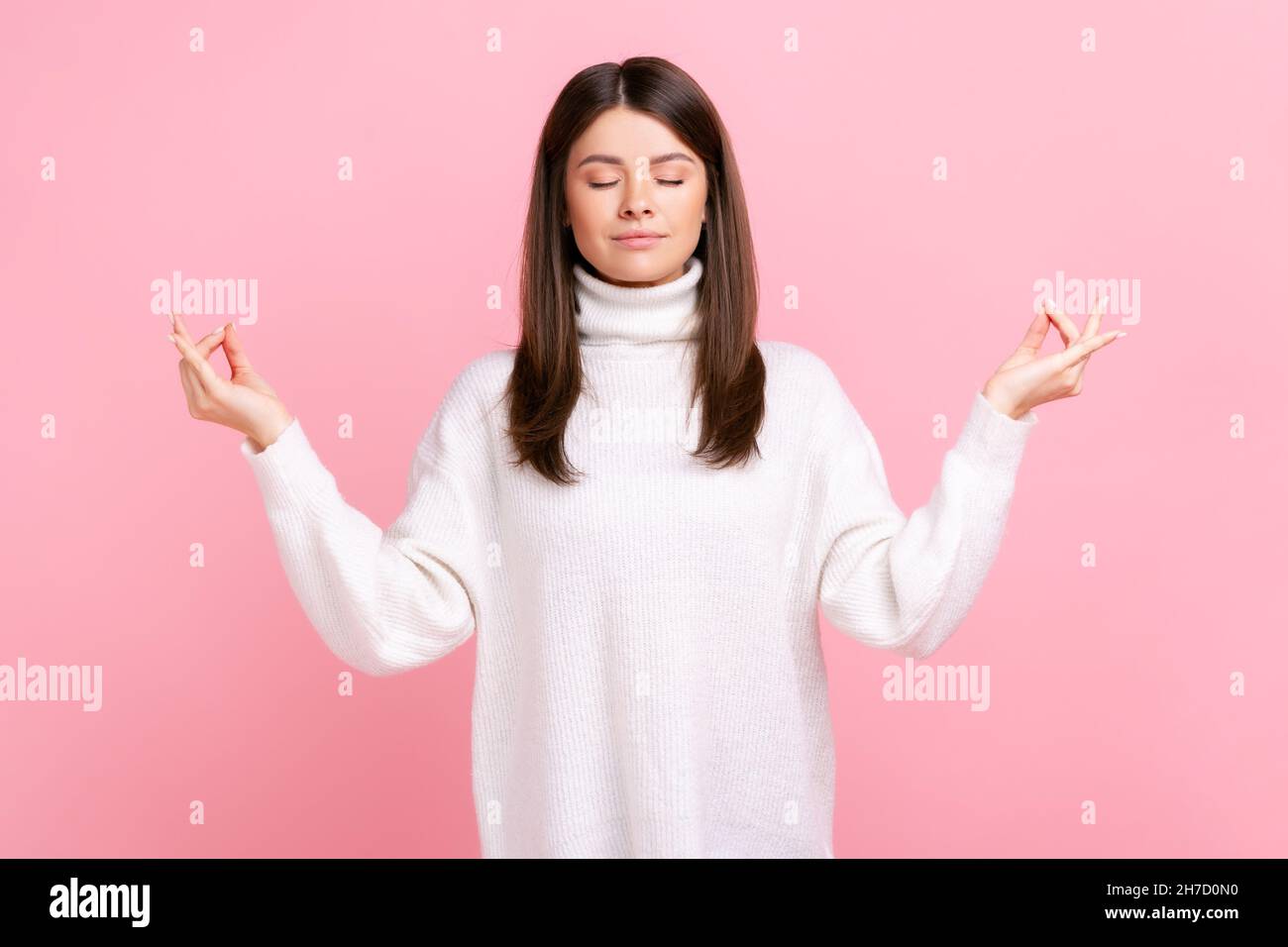 Relaxed girl with dark hair doing yoga, breathing, keeping eyes closed ...