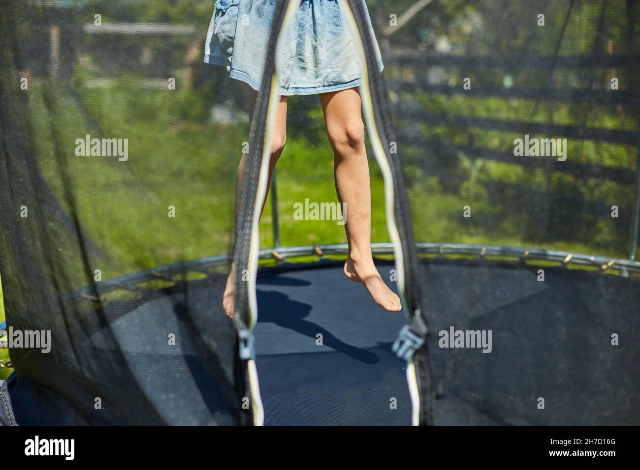 Leg of little child jumping on trampoline in the backyard of the house ...
