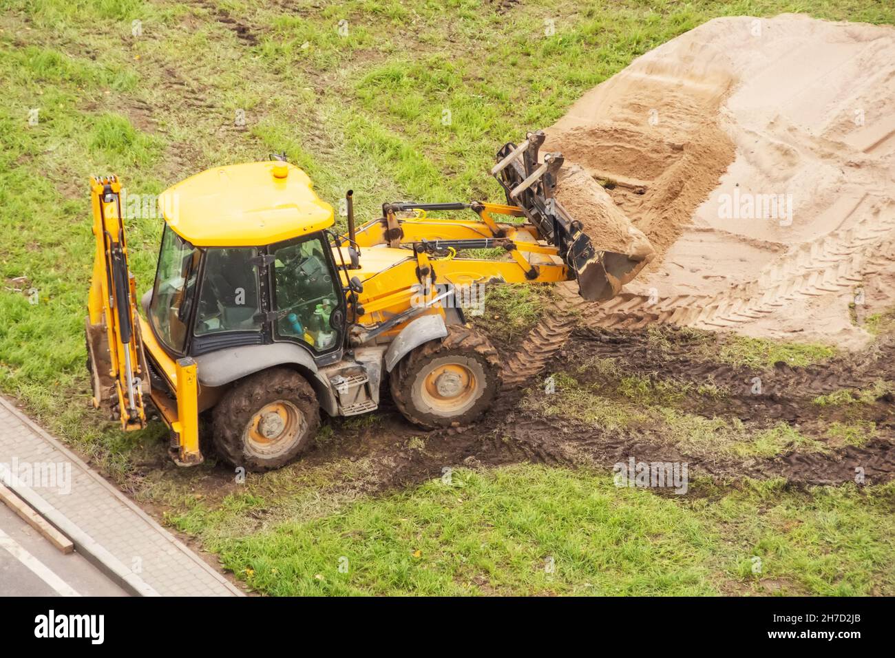 Tractor with sand bucket levels the surface next to the grass Stock ...