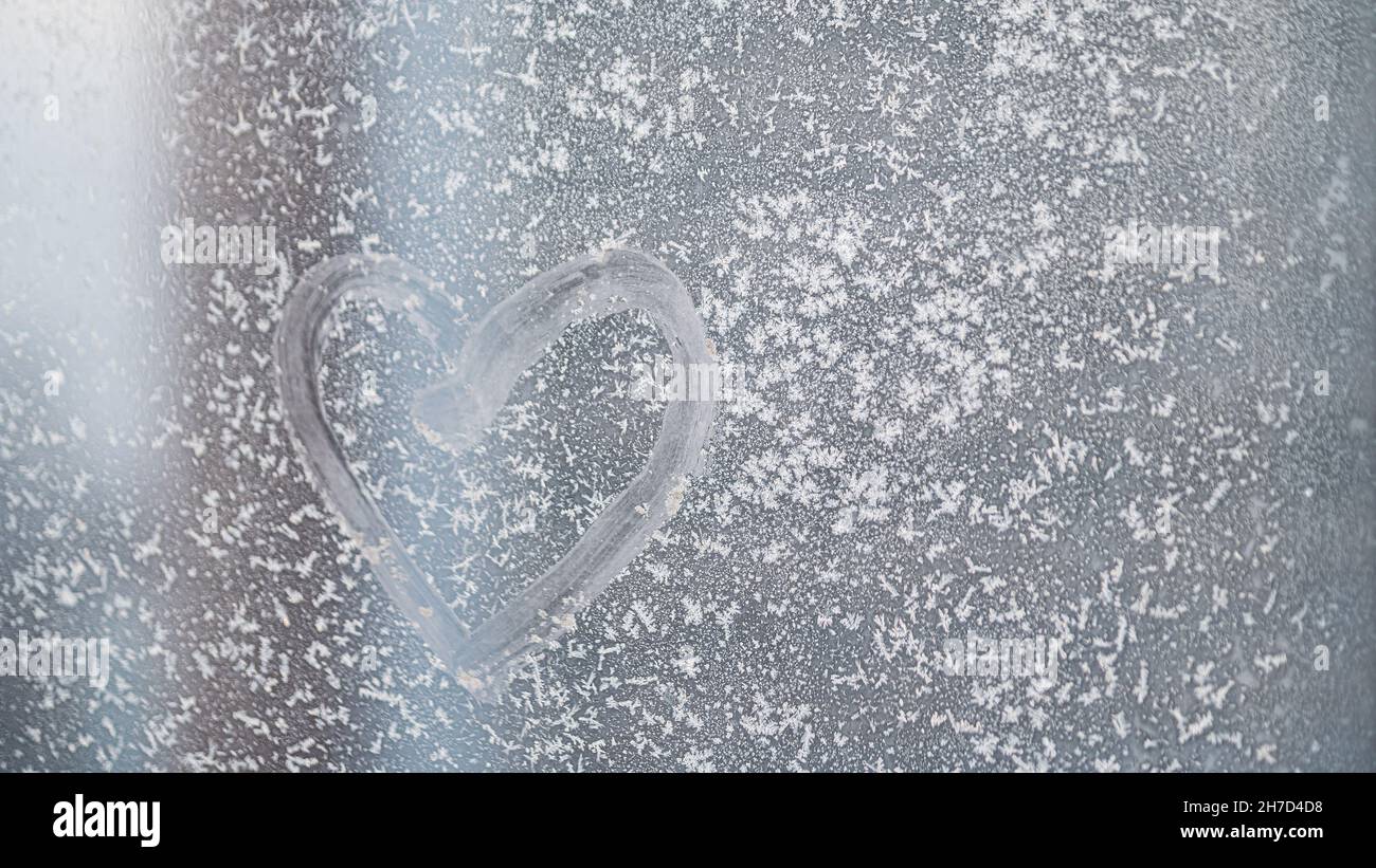 A heart is drawn on a frozen winter window. Valentine's day message ...