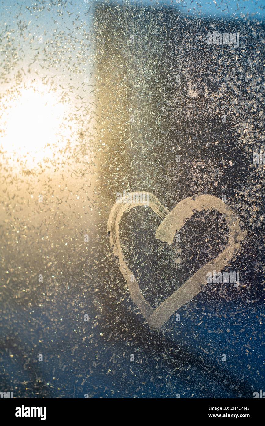 A heart is drawn on a frozen winter window. Valentine's day message ...