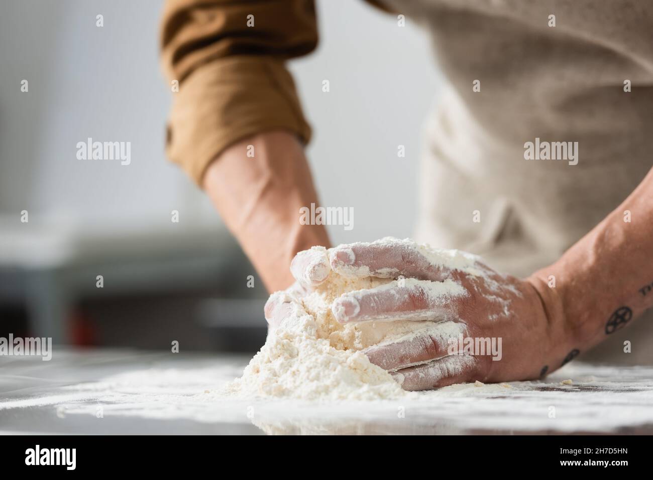 Cropped view of blurred chef making dough on kitchen table Stock Photo ...