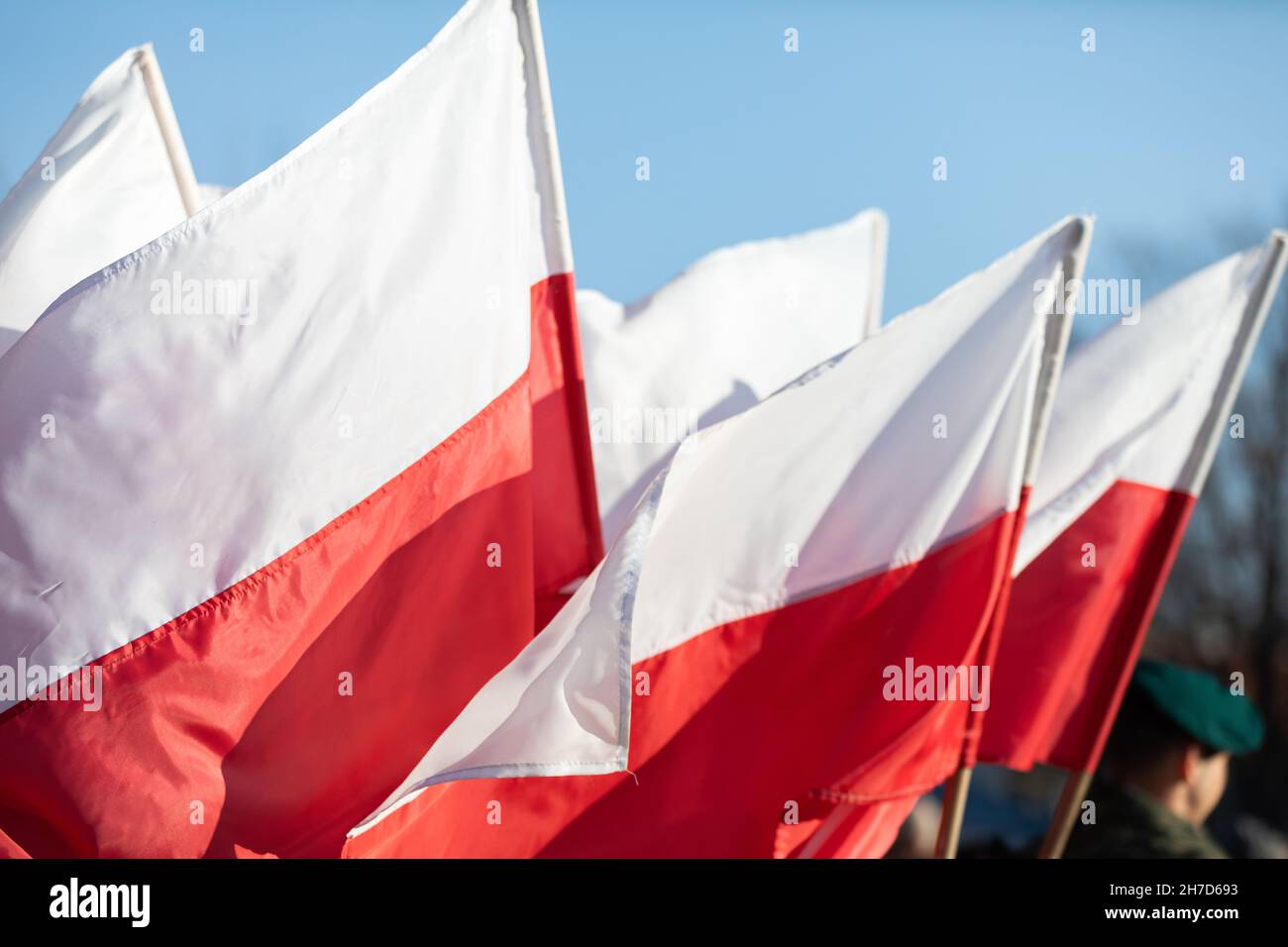 Polish flags are flying and in the background stands a soldier in ...