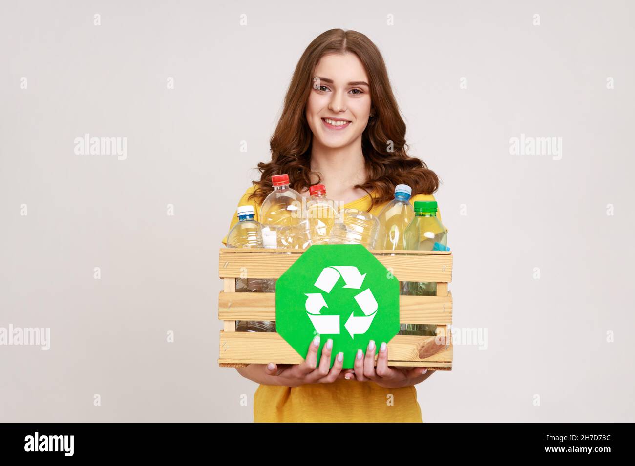 Smiling positive teenager girl with brown hair holding box of plastic ...