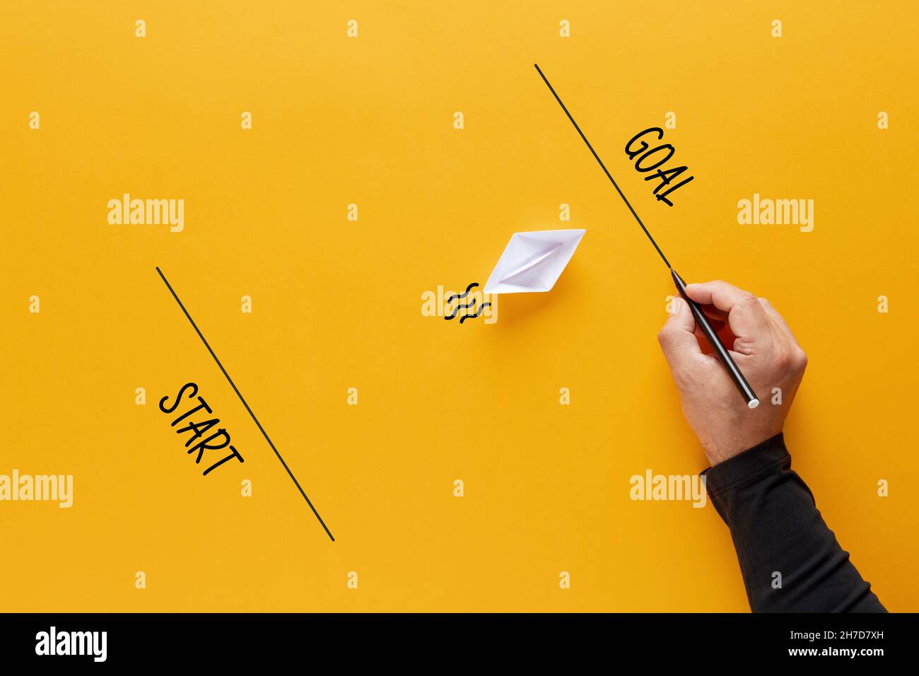 Origami paper boat floats from the start line towards goal line drawn ...