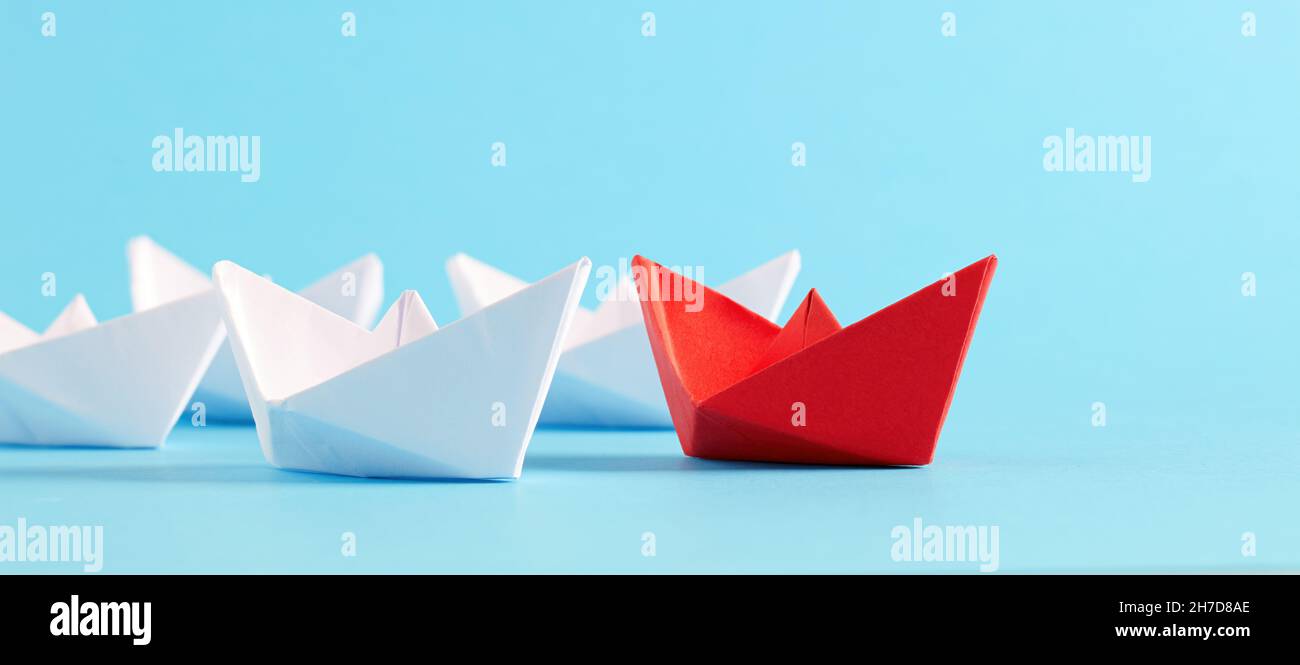 Red paper boat leads white paper ships. Leadership, collaboration ...