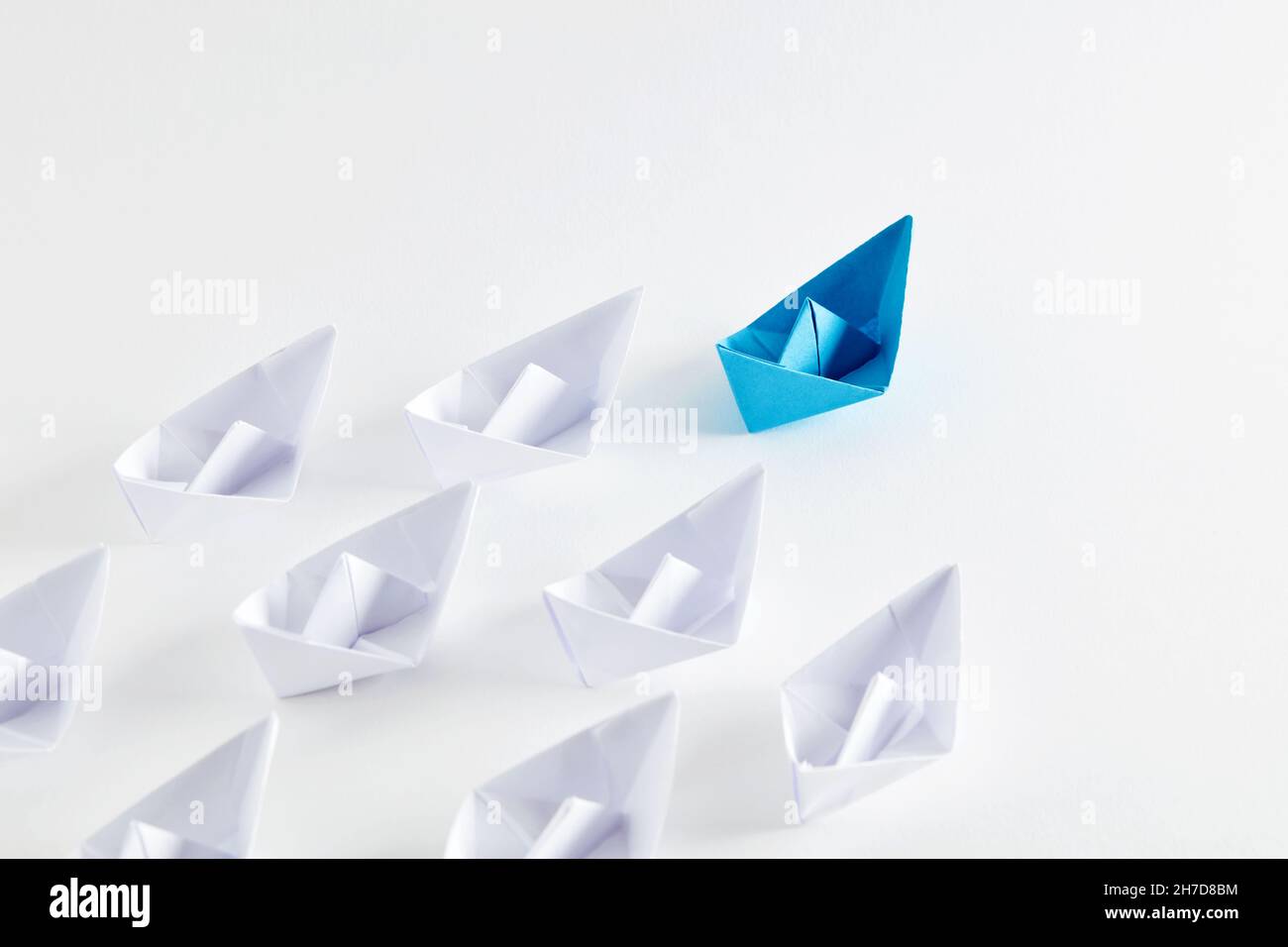 Blue paper boat leads white paper ship fleet. Teamwork, collaboration ...