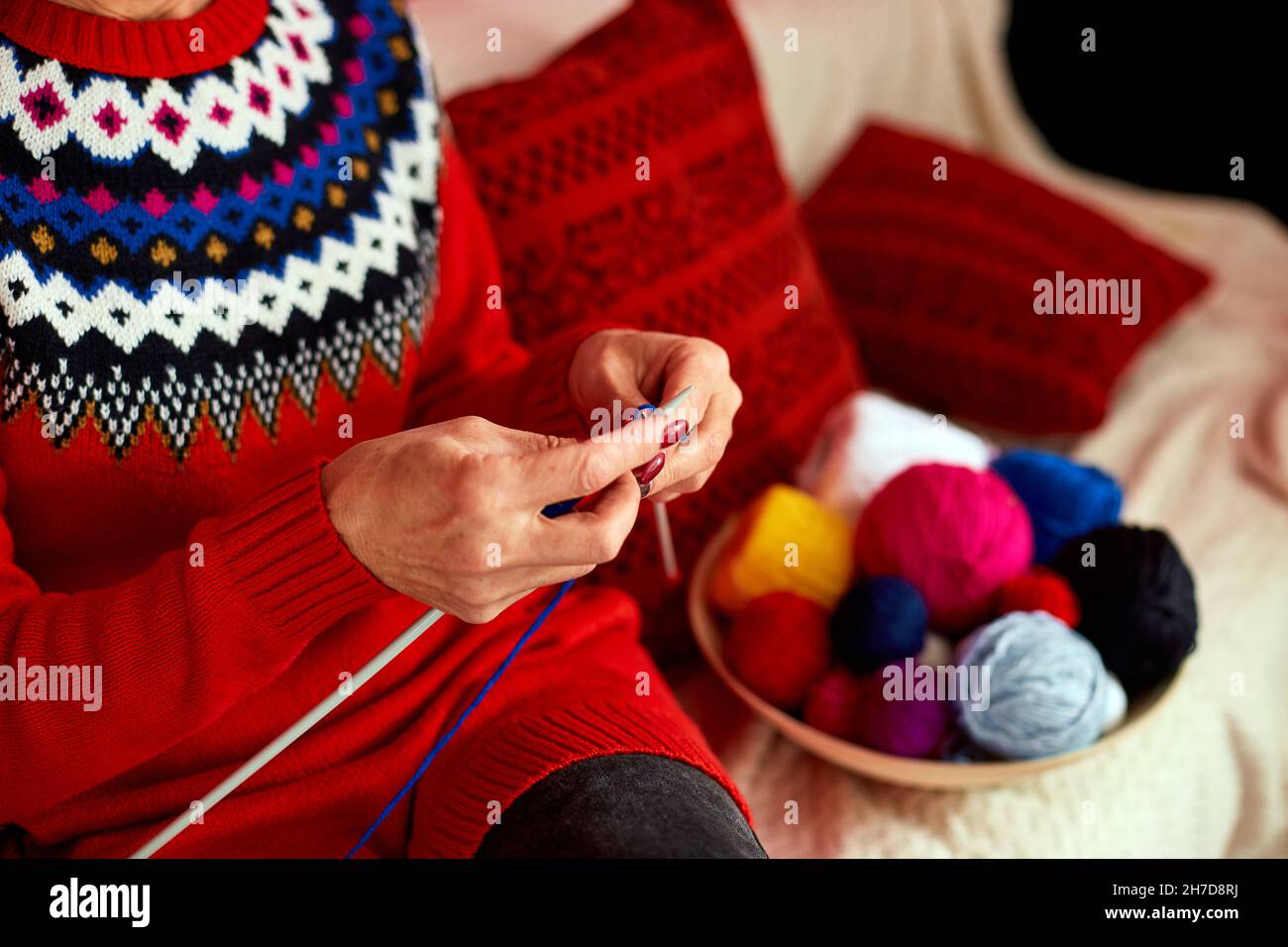 Hand of Mature female sitting in comfortable sofa and knitting while ...