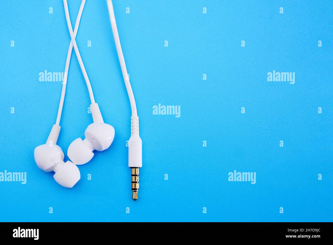Top view on white wire earbuds on blue background. White earphones and ...