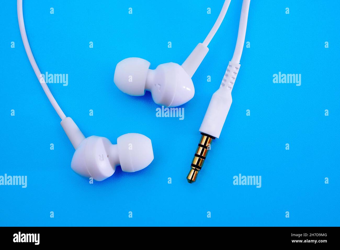 Top view on white wire earbuds on blue background. White earphones and ...