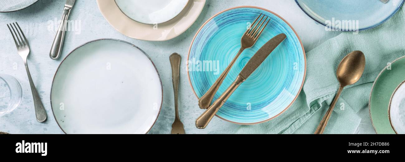 Tableware and cutlery panorama, shot from the top, with a vibrant blue ...