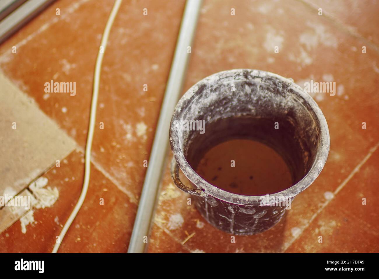 Dirty black plastic bucket with drips on brown floor Stock Photo - Alamy