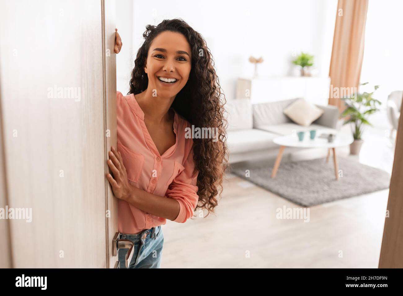 Cheerful lady inviting people to enter home Stock Photo - Alamy