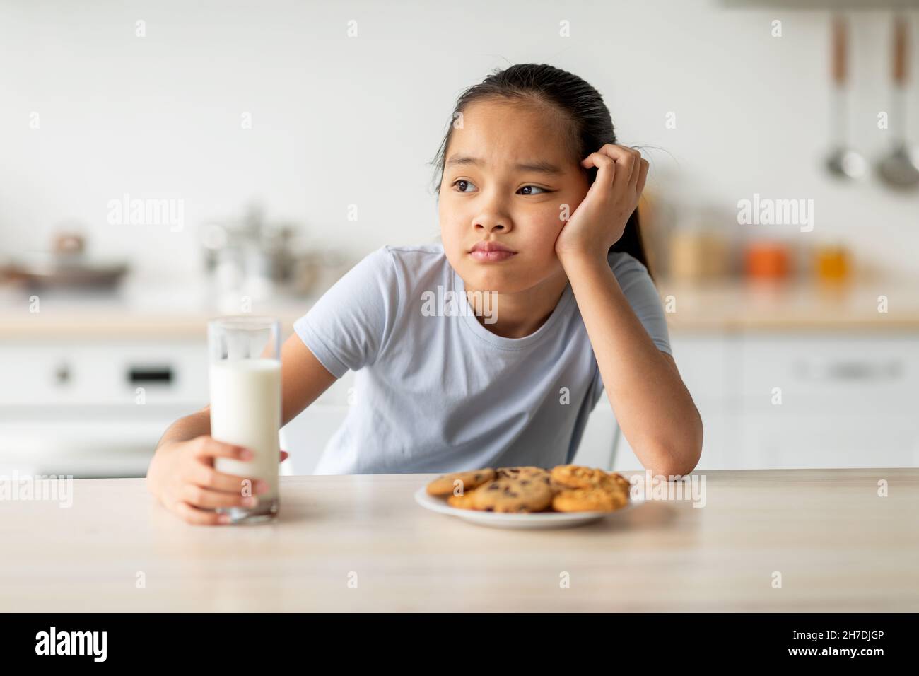 Portrait of sad asian girl holding glass of milk and dreaming, looking ...