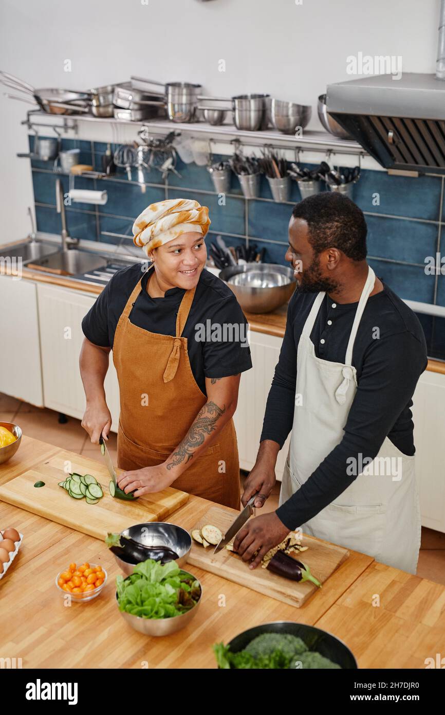 Vertical high angle portrait of two people enjoying cooking vegetables ...