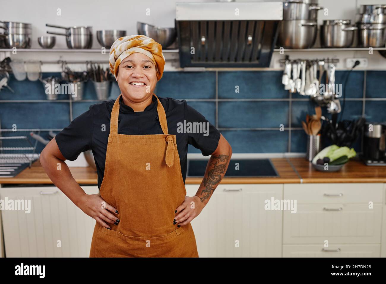 Waist up portrait of smiling female cook looking at camera while posing ...
