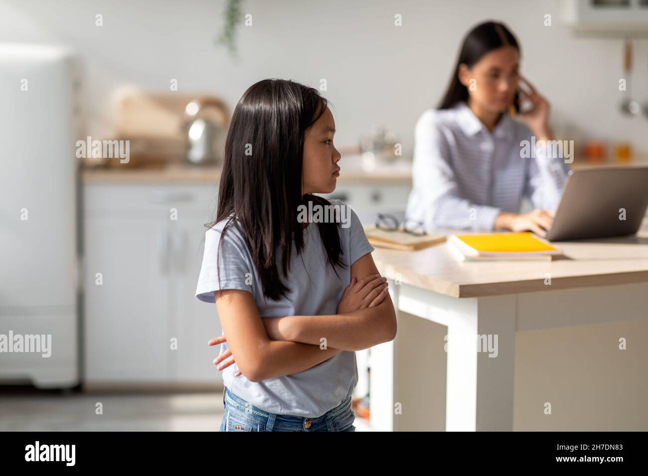 Sad asian girl taking offence at her busy mother working online on ...