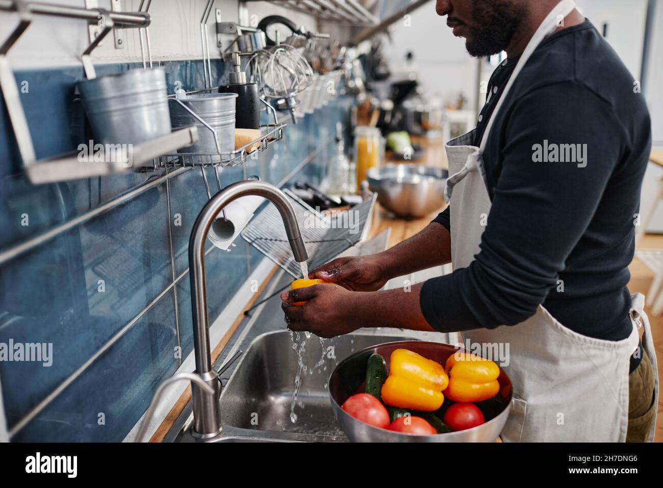 Side view portrait of African-American man washing fresh vegetables ...