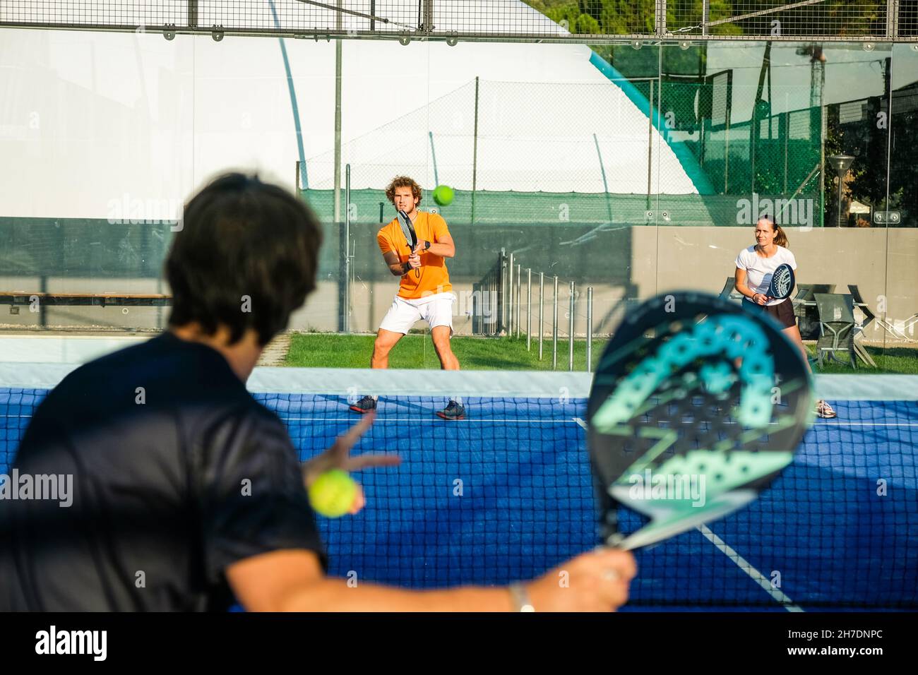 Mixed padel match in a blue grass padel court - Beautiful girl and ...