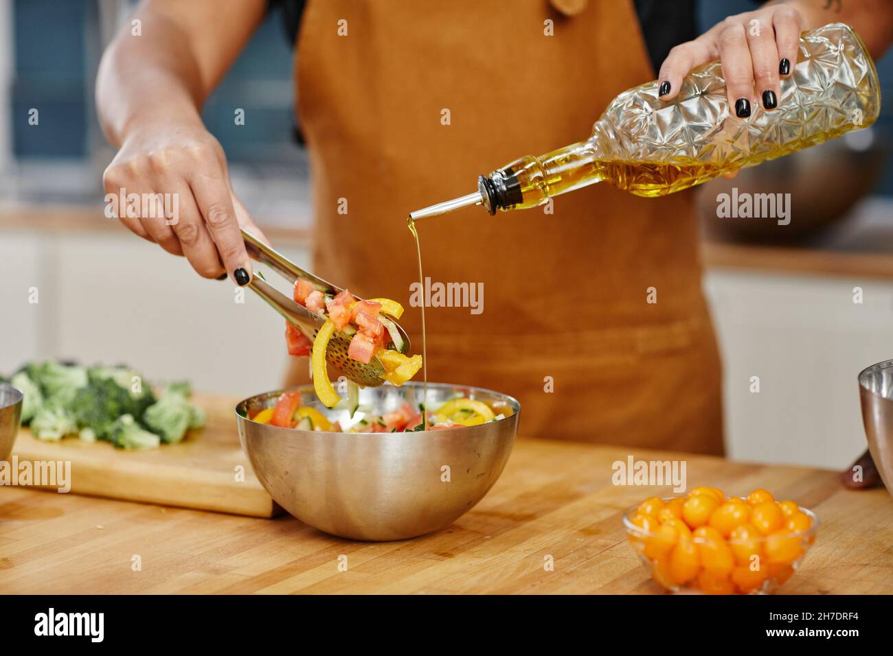 Close up of unrecognizable woman adding olive oil to salad while ...