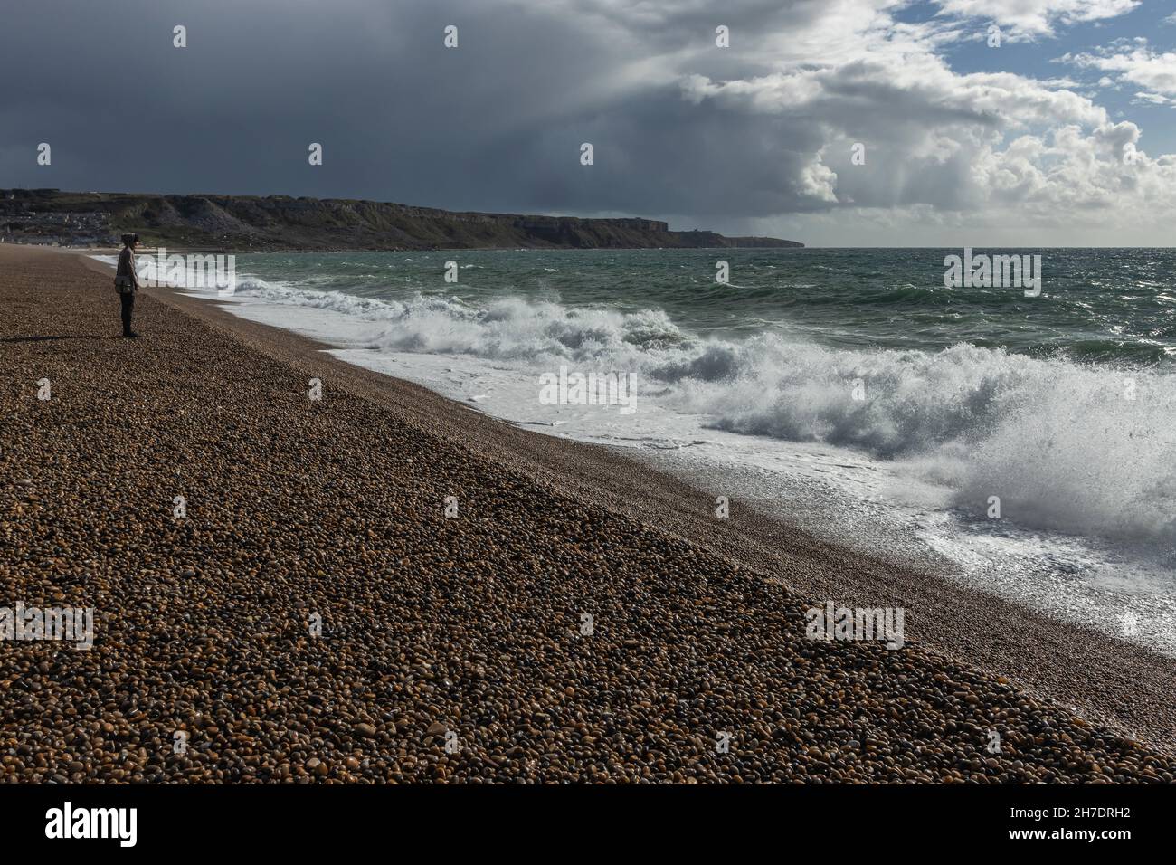 Female watching waves at empty Chesil Beach (Portland Stock Photo - Alamy