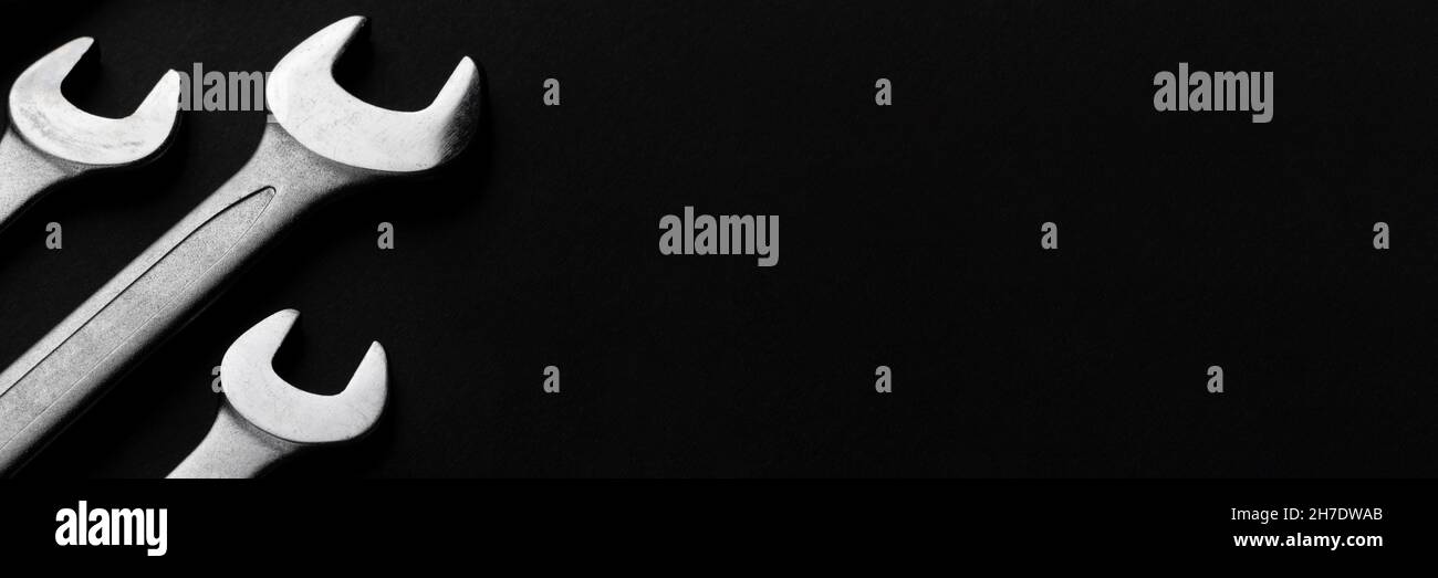 Steel wrenches on black background closeup. Wide panoramic banner with ...