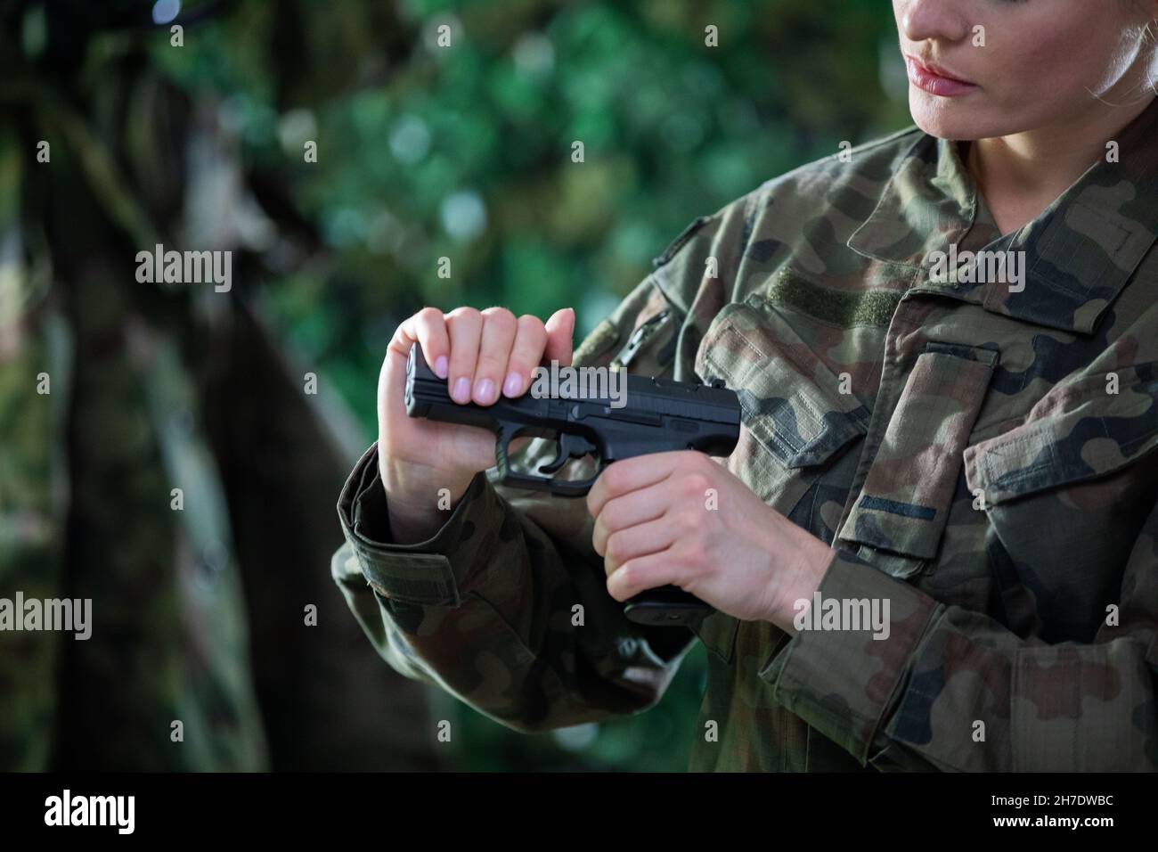 A lady soldier watches and inspects a gun. A soldier in full uniform ...