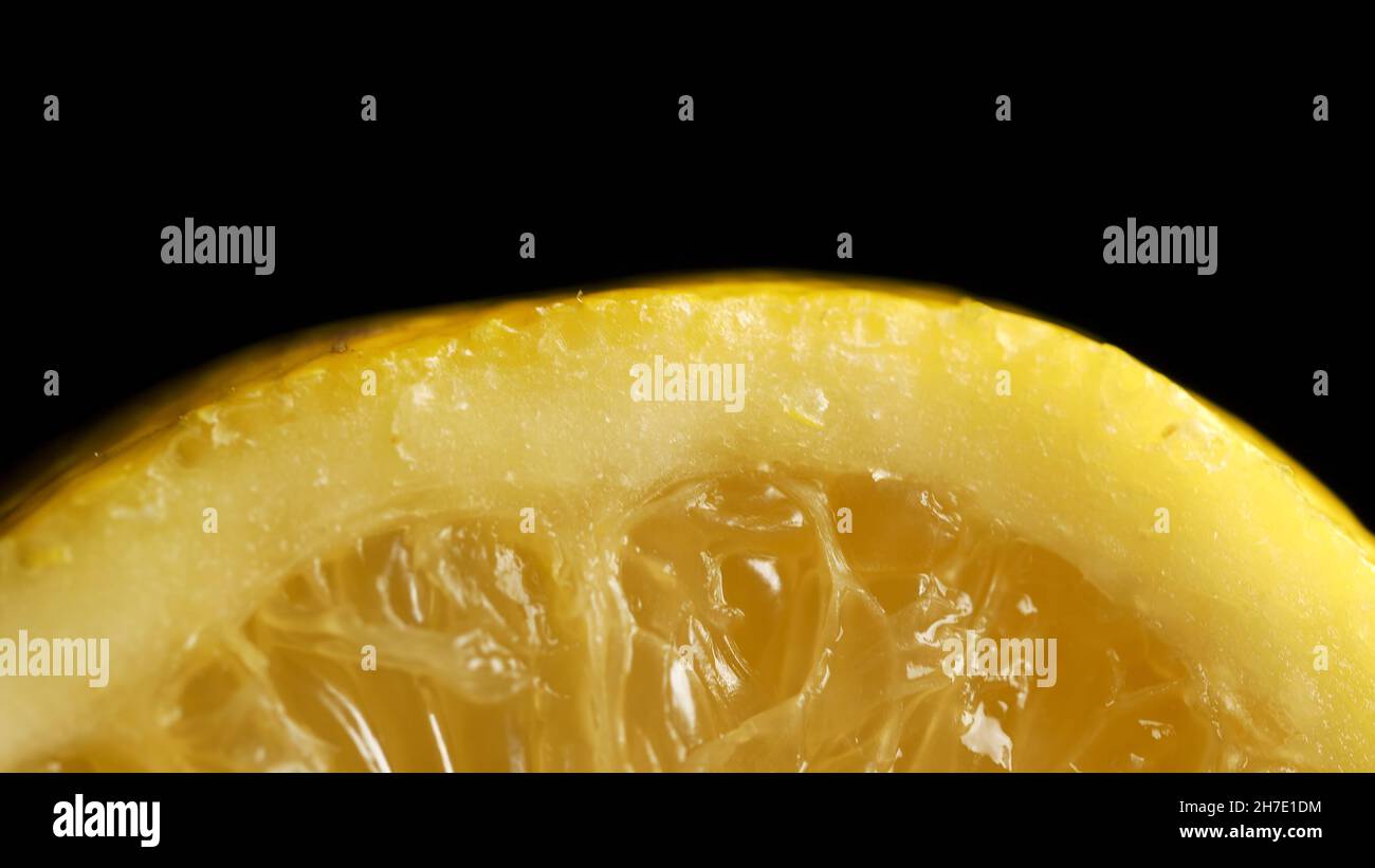 A single fresh yellow lemon on a wood grain table against a black ...