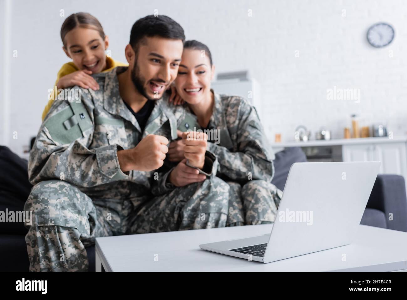Laptop near man in military uniform showing yes gesture near wife and ...
