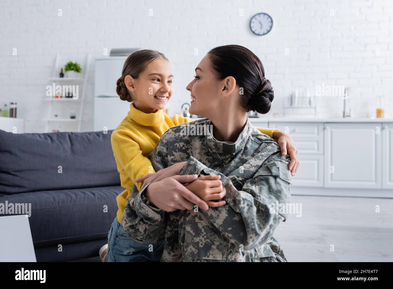 Smiling kid hugging mom in military uniform at home Stock Photo - Alamy
