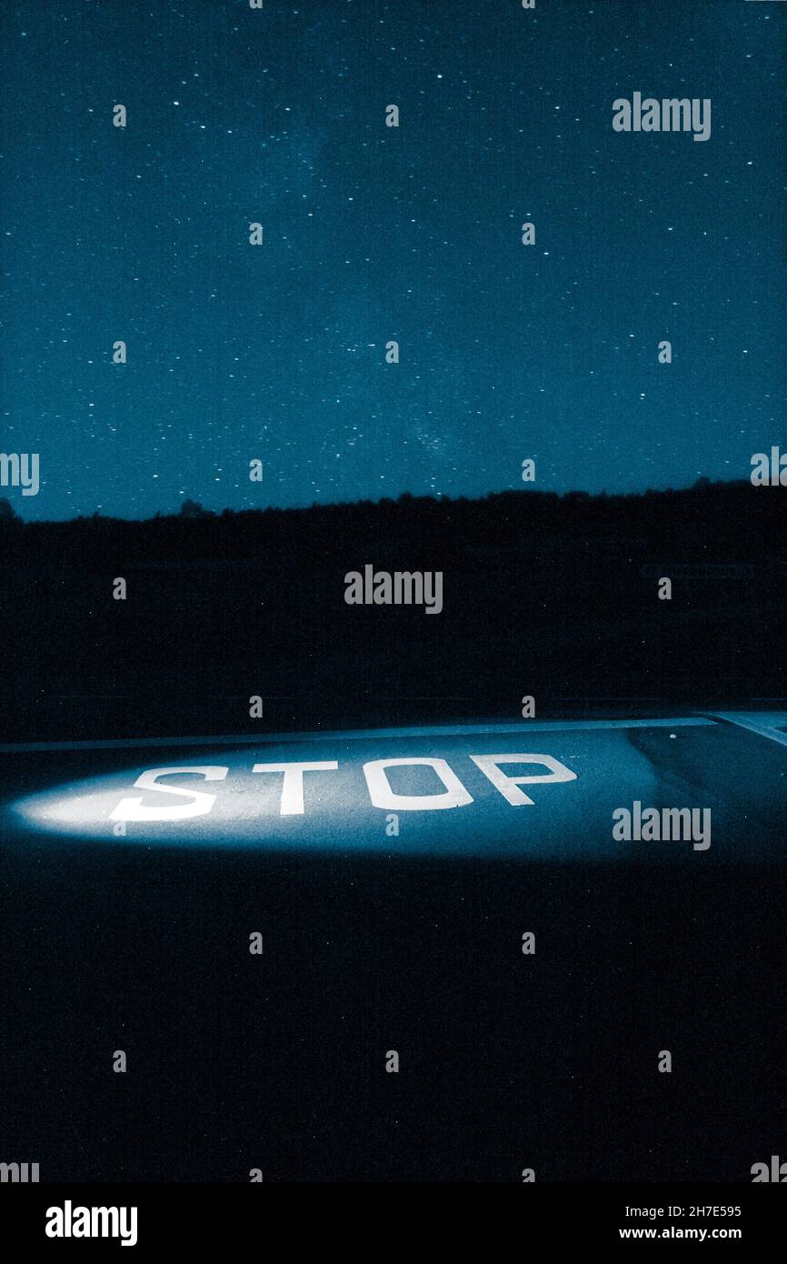 Vertical shot of an illuminated STOP sign on the road under a starry ...
