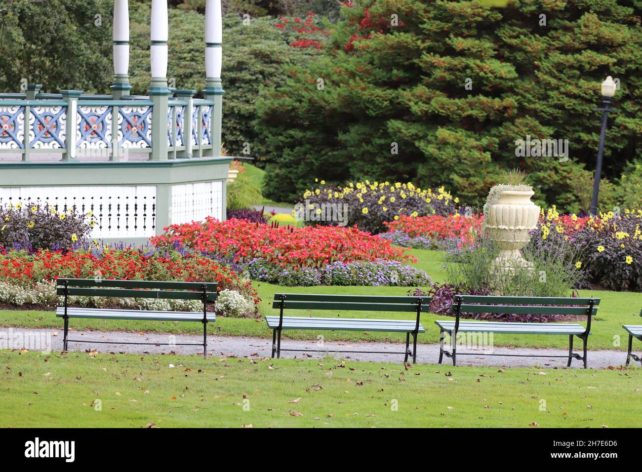 Beautiful park with a gazebo, benches, dense trees and colorful flowers ...