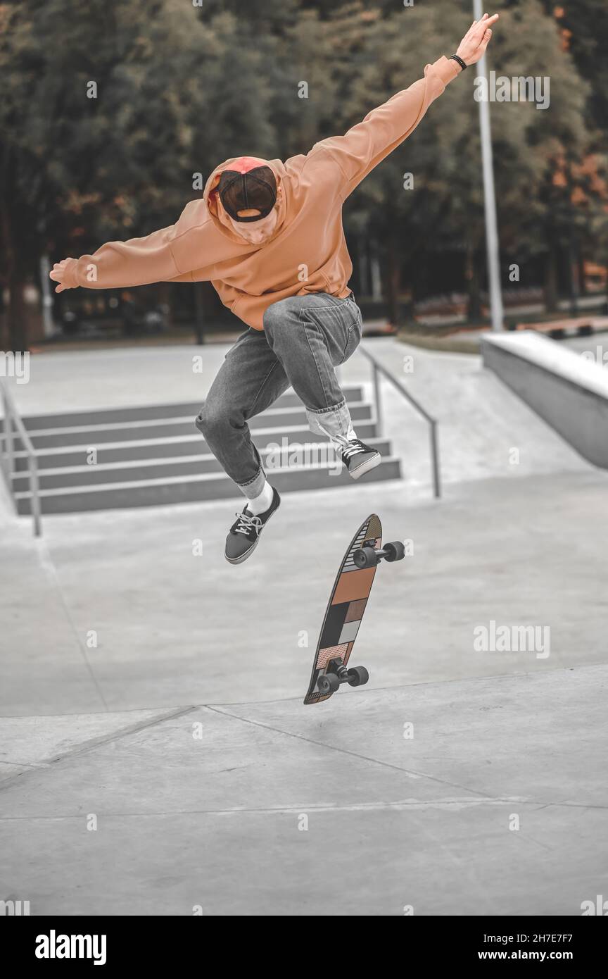 Guy bouncing high in air and skateboard falling below Stock Photo - Alamy