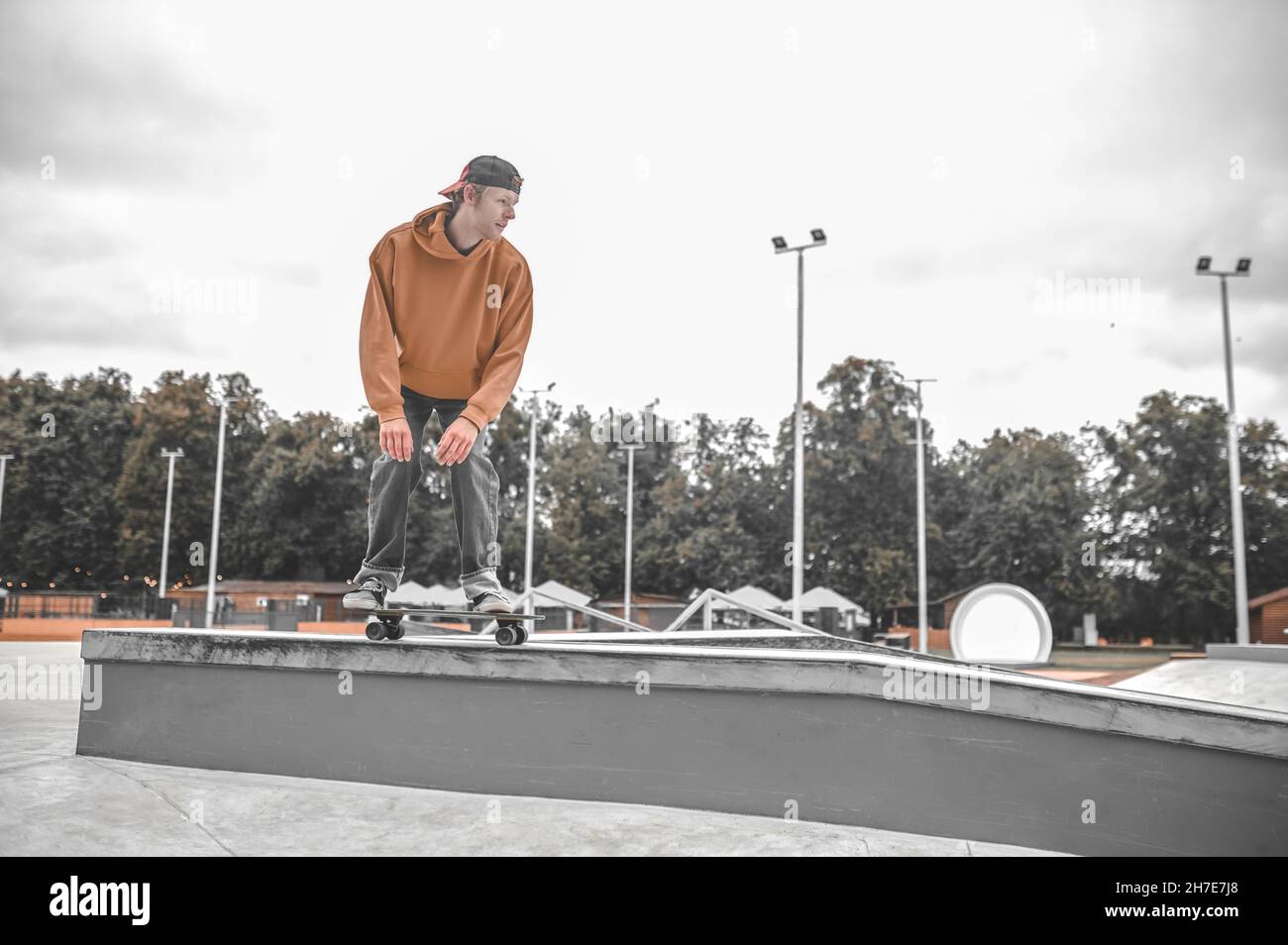 Guy on skateboard crouched down sliding on bollard Stock Photo - Alamy