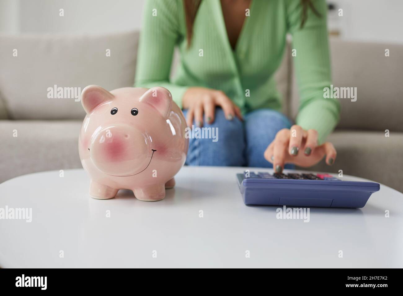 Woman calculate expenses from piggybank on machine Stock Photo - Alamy