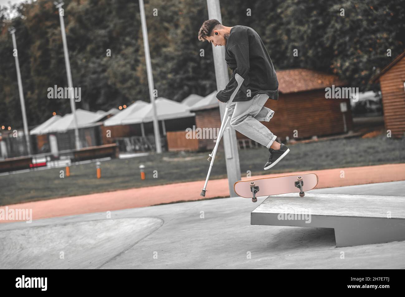 Guy on crutches while jumping on skateboard from springboard Stock ...