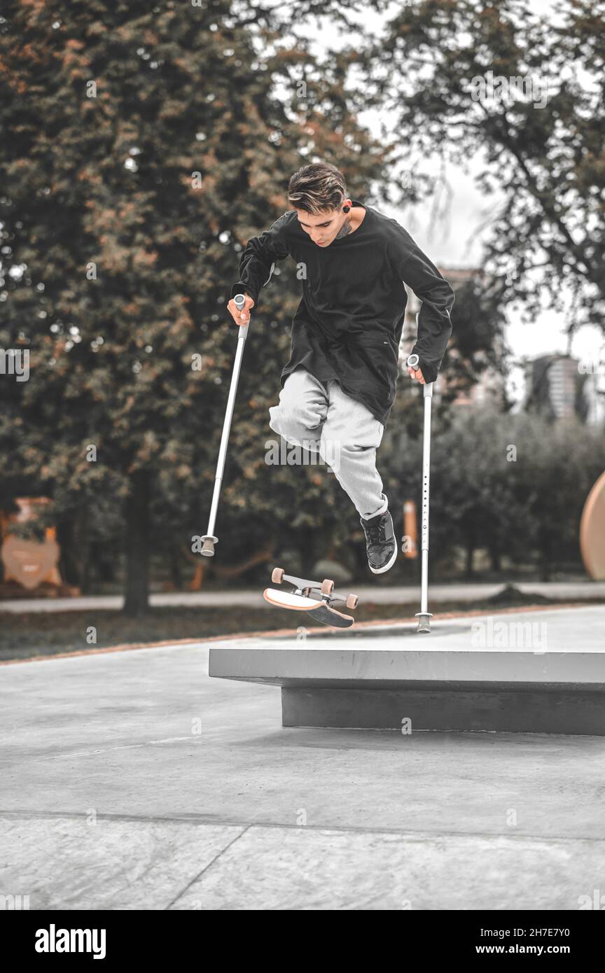 Disabled guy on crutches jumping on skateboard from springboard Stock ...