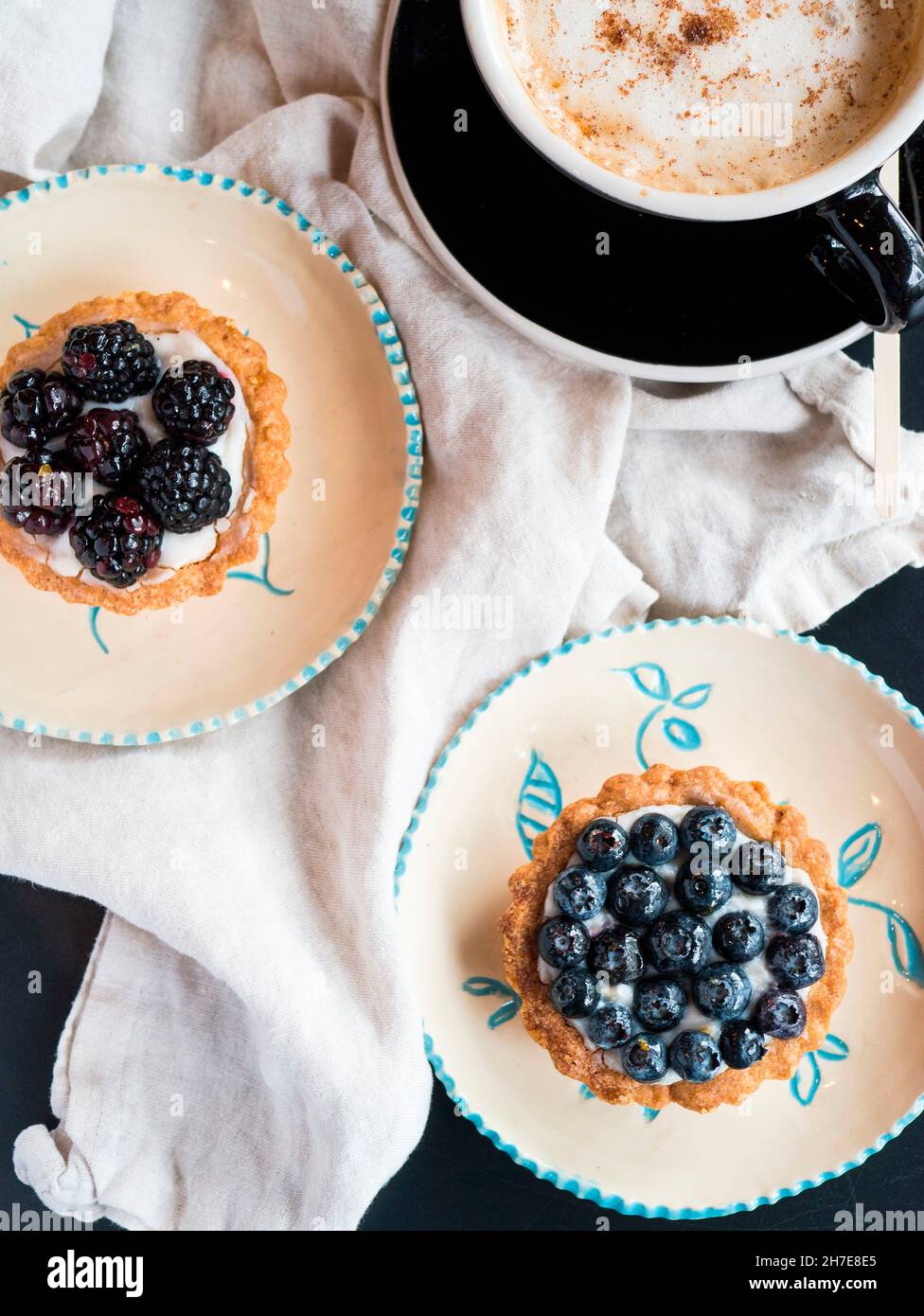 Two berry tarts and a cappuccino Stock Photo - Alamy