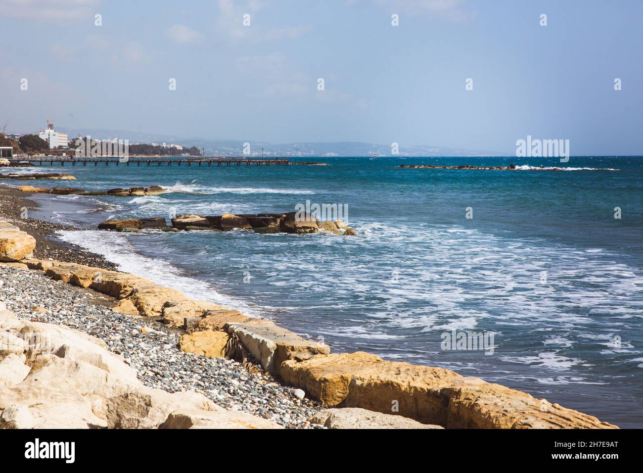 Empty stone beach on Limassol seafront on a sunny spring day. Waves at ...