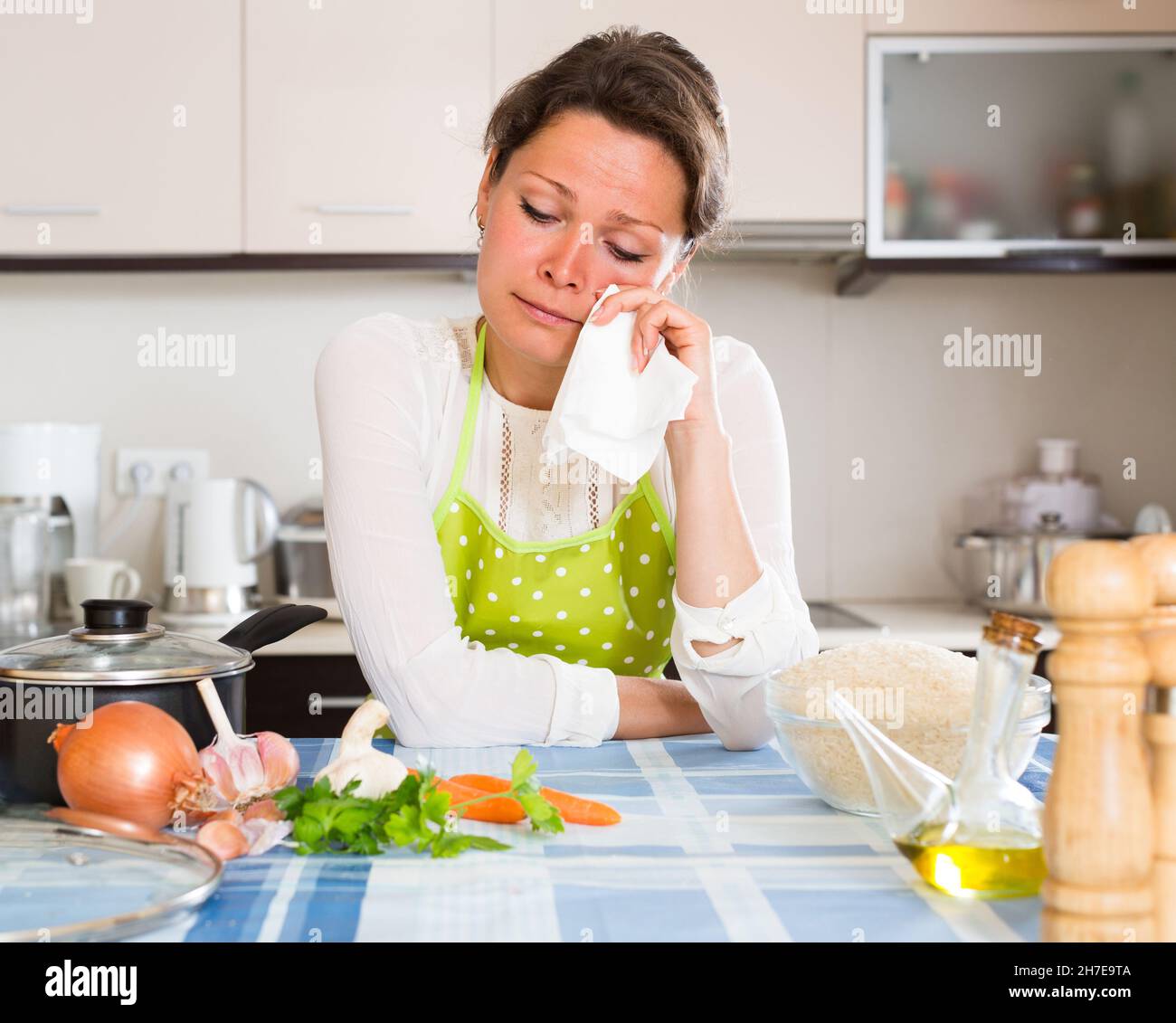 Sad woman cooking rice in the kitchen Stock Photo - Alamy