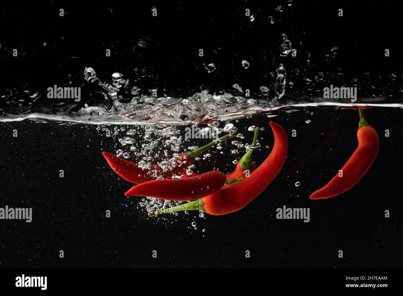 Red chili falling into water creating movement, motion and splashes ...