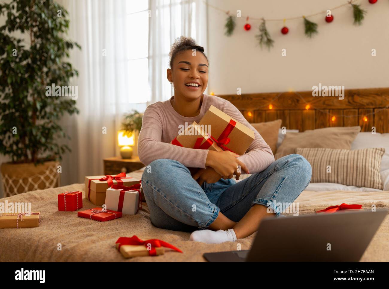 Distance holiday celebration. Excited black lady hugging gift boxes and ...